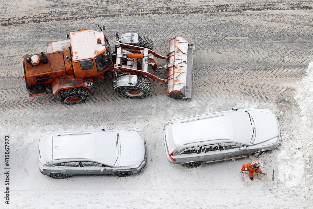 Worker and snow plow machine removing the snow on the parking lot, top ...