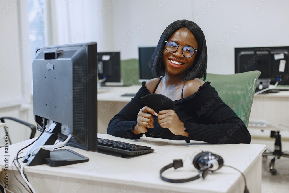 African woman sitting in computer science class. Lady in glasses smiles ...
