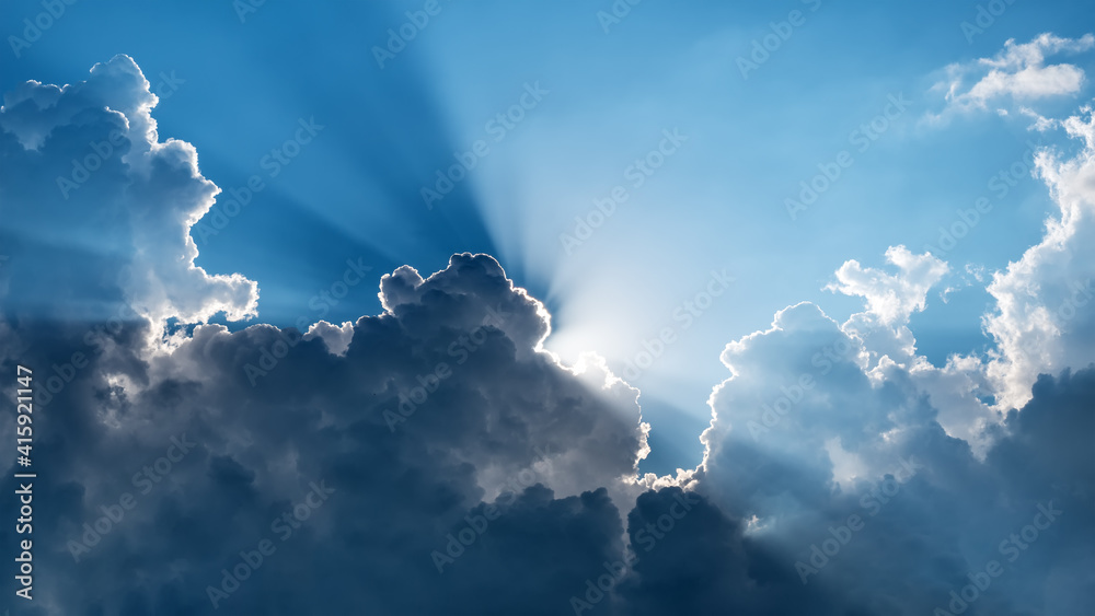 Sun behind dark clouds with sun rays on blue sky background Stock Photo | Adobe Stock