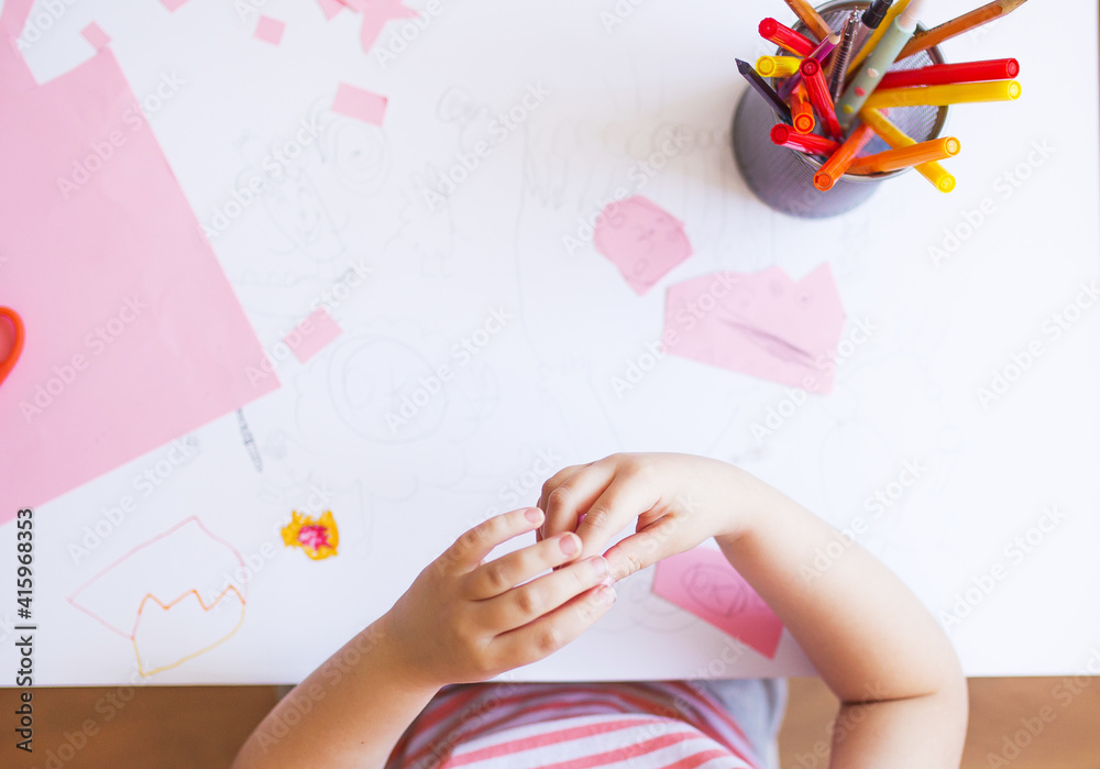Top view of a child working on her project on the table with scissors ...