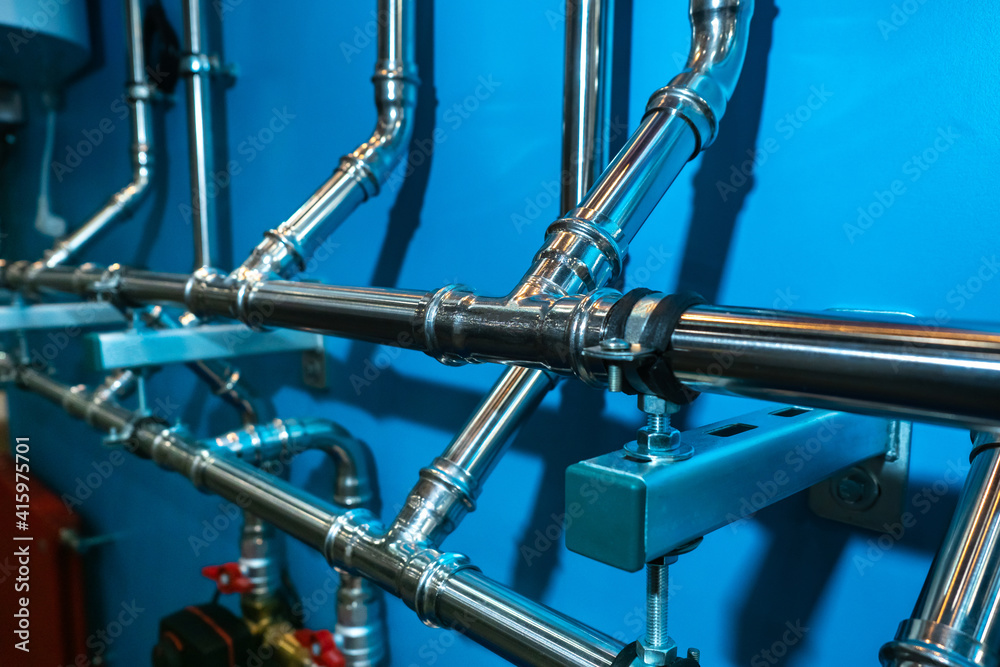 Chrome pipes and fittings on a blue background. Piping with many ...