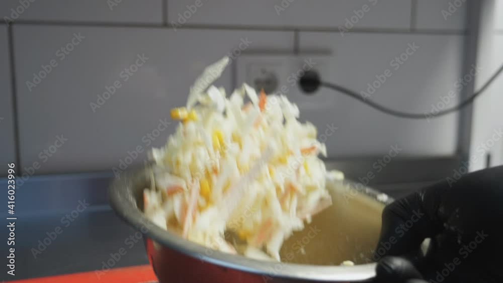 Male hand of cook in glove tossing ingredients and stirring them in ...