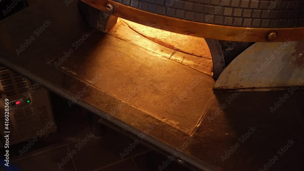 Putting fresh pizza into hot oven. Overhead view of cook putting raw ...