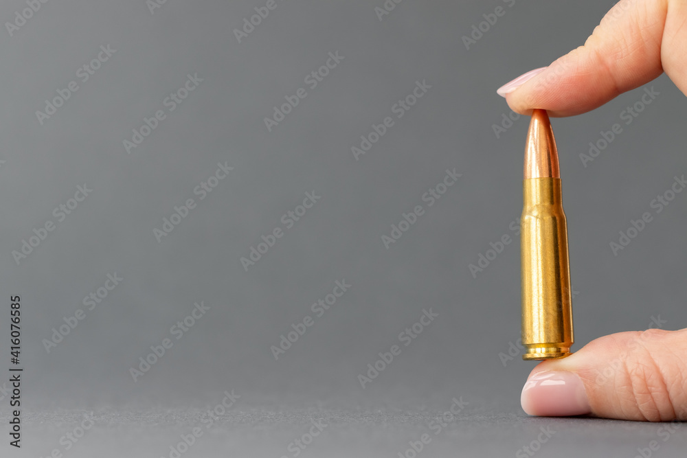 Hand with bullet on gray background. Cartridge 7.62 caliber for ...