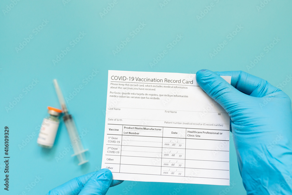 Doctor is holding a vaccination record card and corona virus vaccine ...