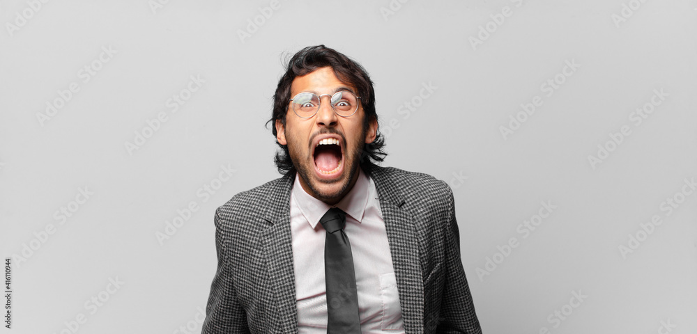 young handsome indian man shouting aggressively, looking very angry ...
