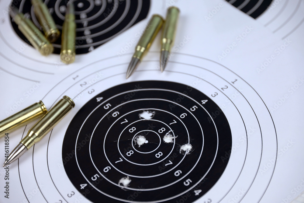 Many bullets on shooting targets on white table in shooting range ...