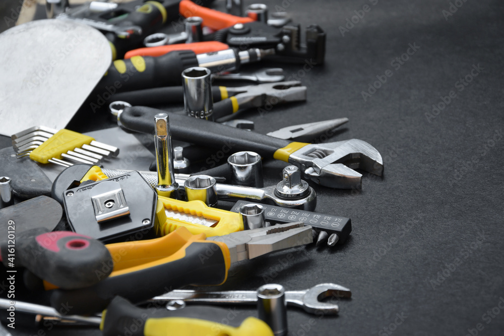 Handyman tool kit on black wooden table. Many wrenches and screwdrivers ...