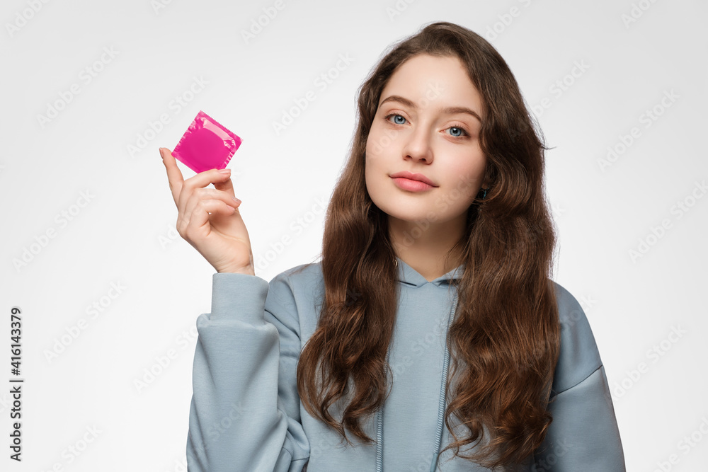 Young woman, teenager with a condom in her hand. Young woman with long ...