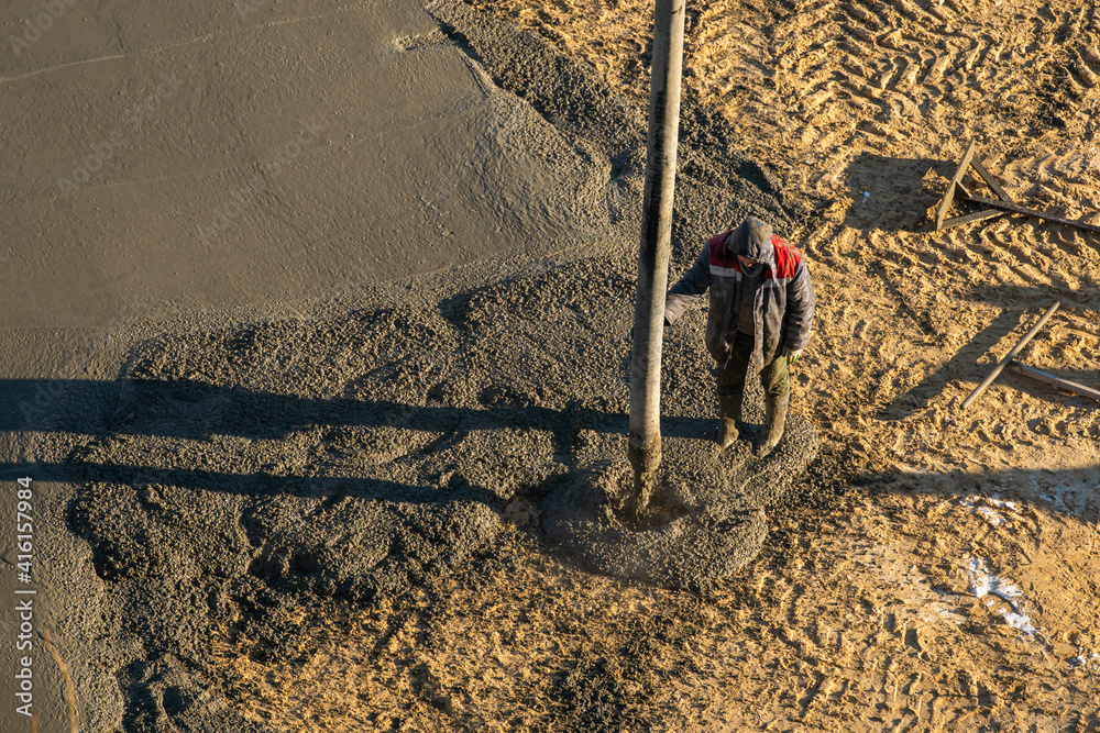Worker pour cement or concrete using a pump tube on a building ...