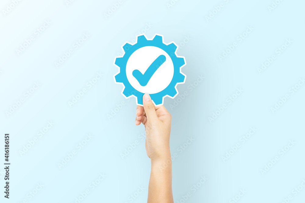 Hand holding paper with icon gear and check mark on light blue ...
