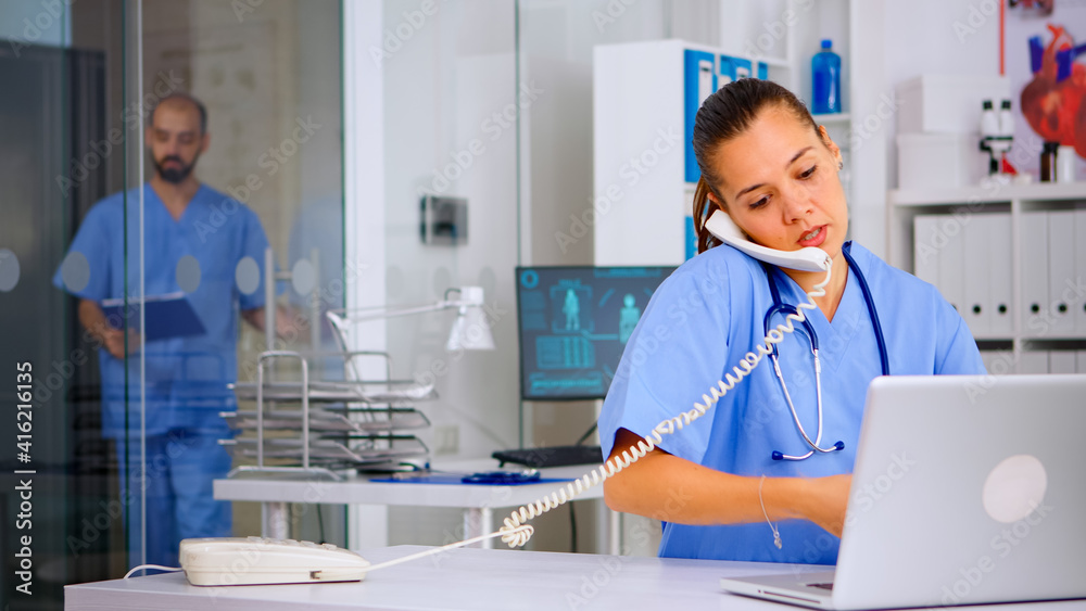 Medical assistant speaking at phone with patient analysing ...
