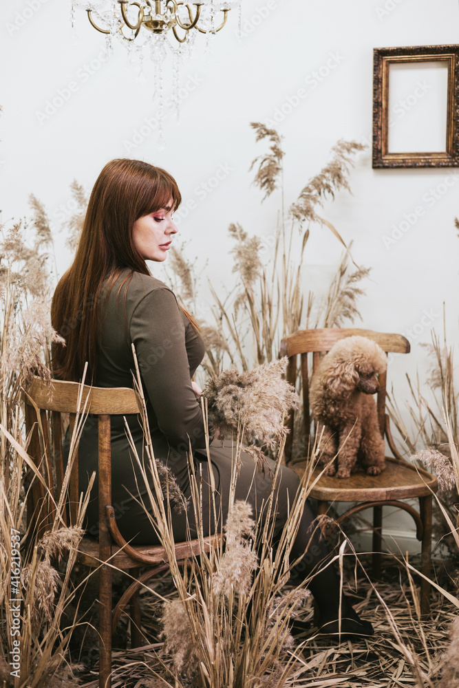 young woman plus size model sits on a chair wearing a green suit in a ...