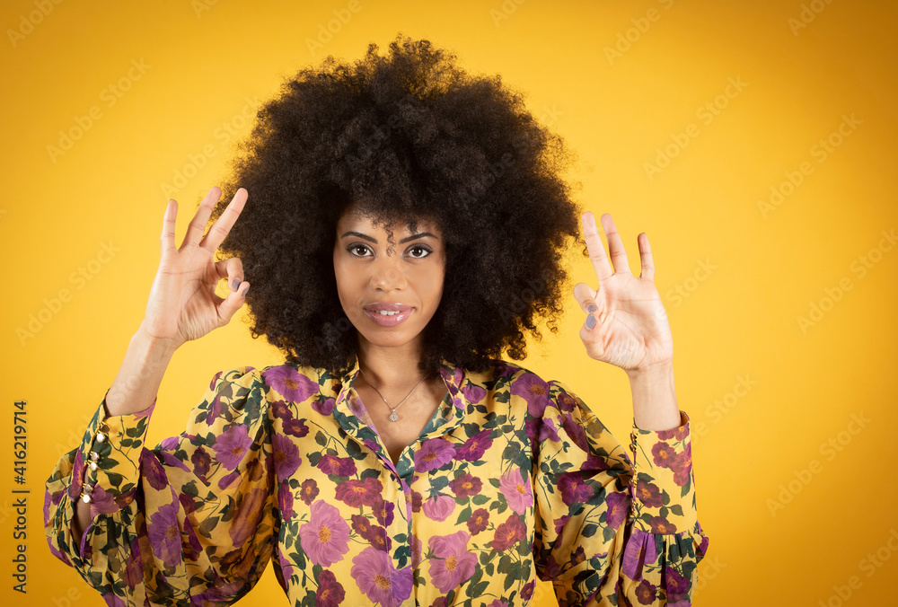 A cheerful smiling African American woman looks through a zero or okay ...