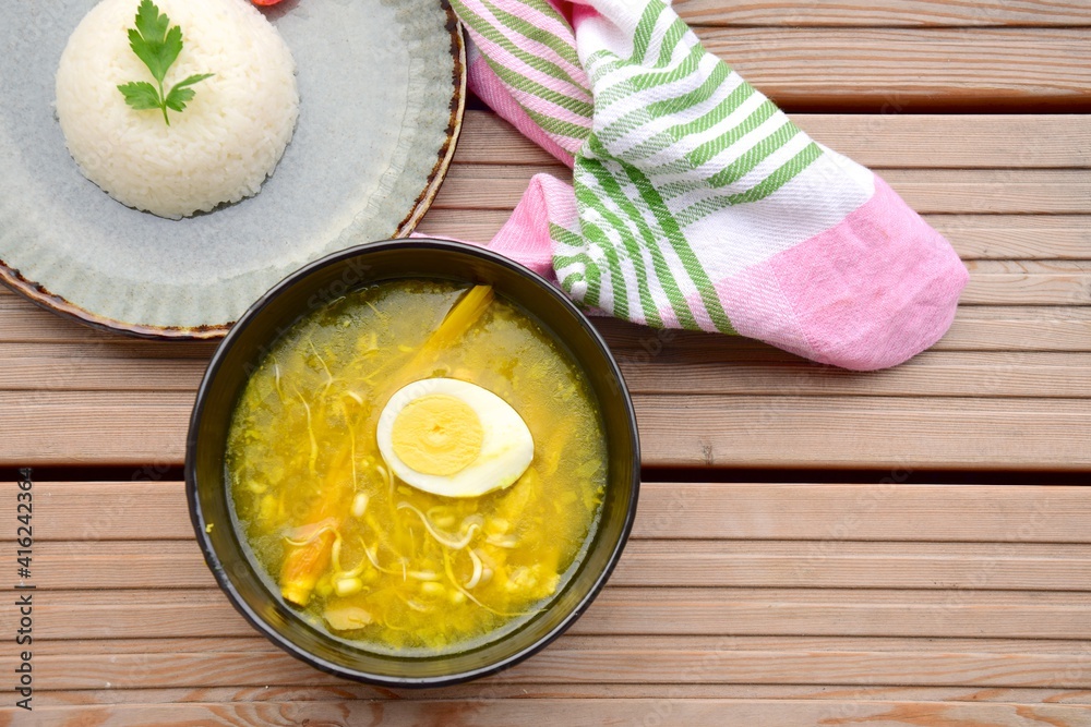 Soto Ayam, yellow spicy chicken soup with egg, tomato, bean sprouts and ...
