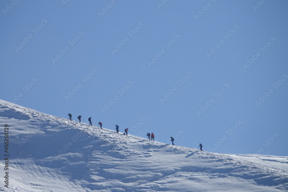 Climb a mountain. A group of hikers climbs the snow-capped peak of Mt ...