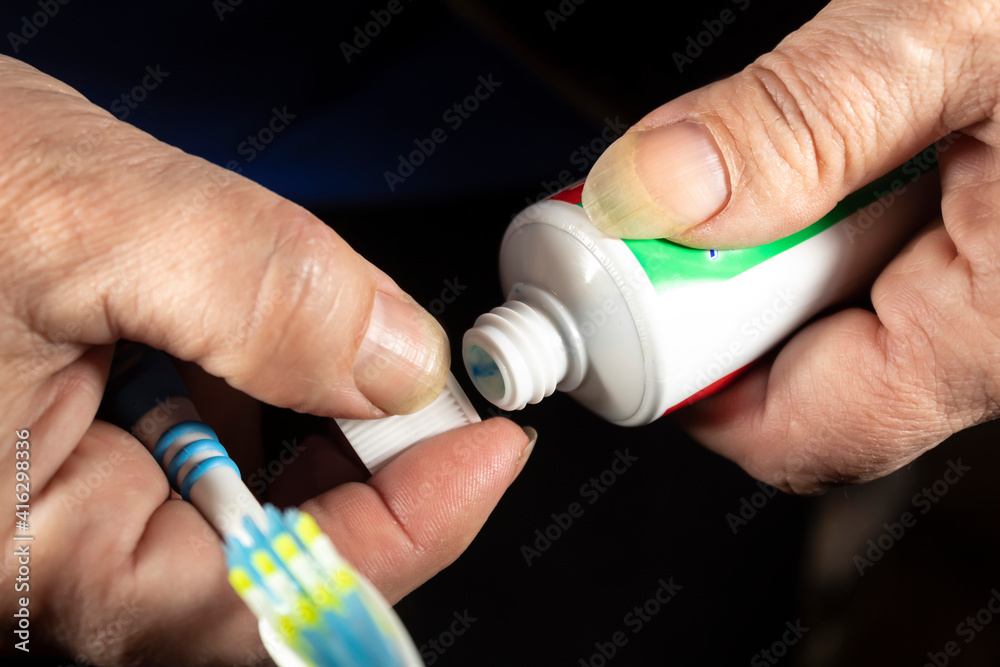 Female hands unscrew a tube of toothpaste and hold a toothbrush. Stock ...