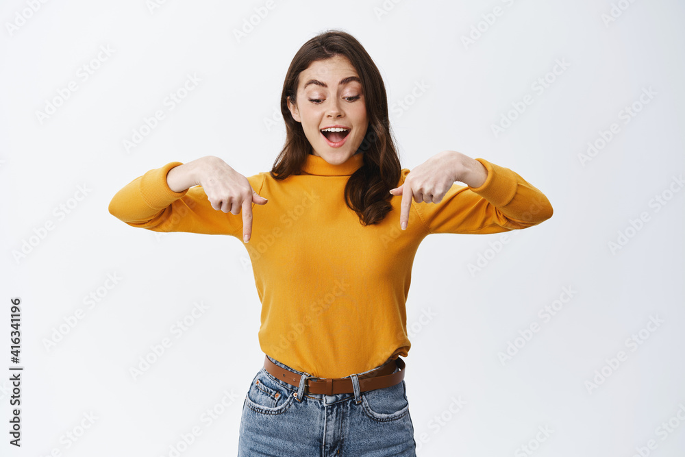Happy and excited young woman looking mesmerized and fascinated down ...