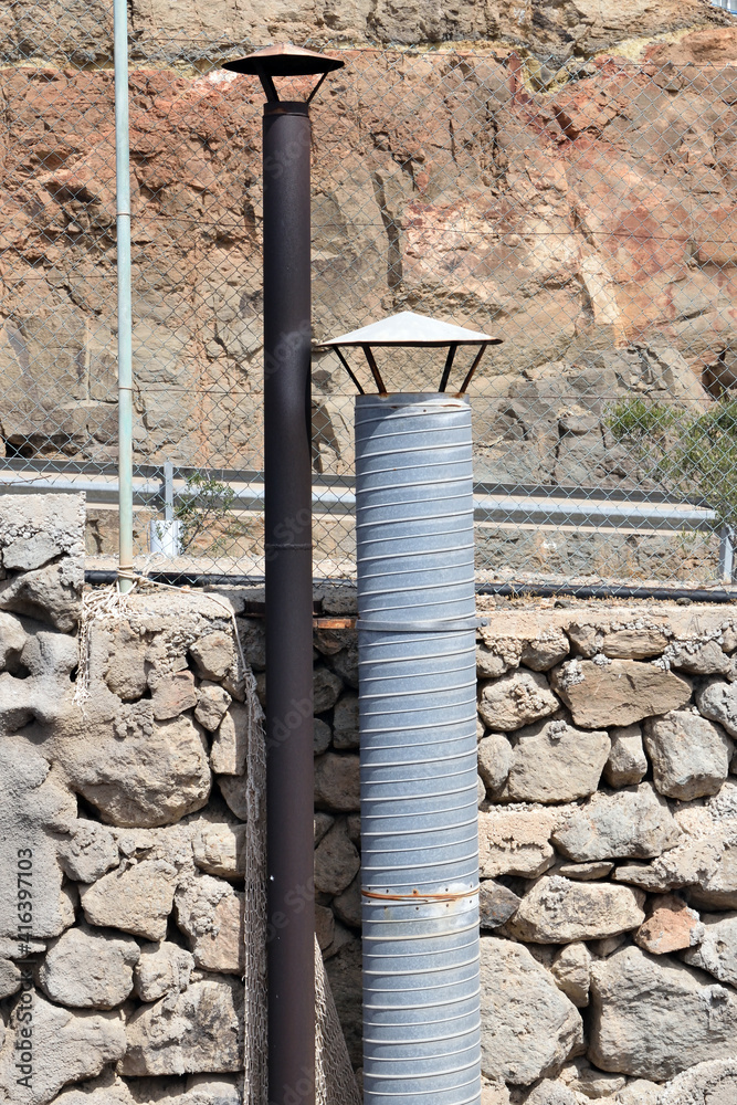 Two Tubular Steel Industrial Chimneys against Rough Stone Wall & Wire ...
