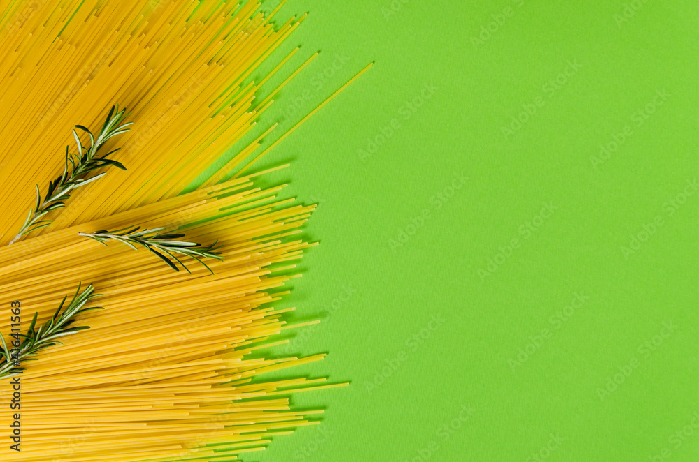 Yellow long spaghetti, rosemary sprigs on a light green background ...