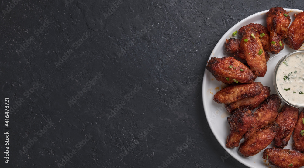 Grilled chicken wings with sauce on black stone background with copy ...
