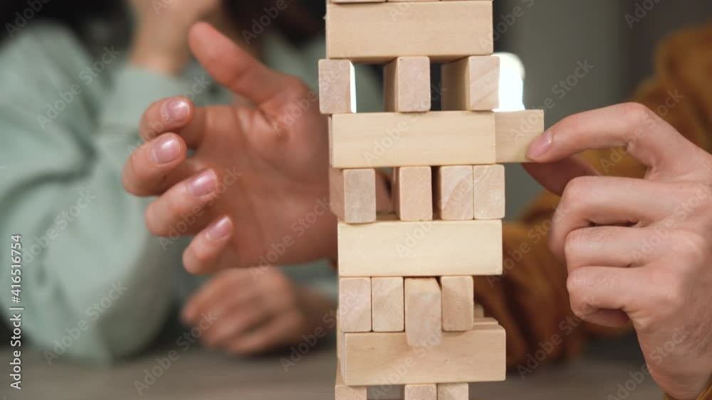of male hands pulling wooden block of jenga game. Tower made of wooden ...