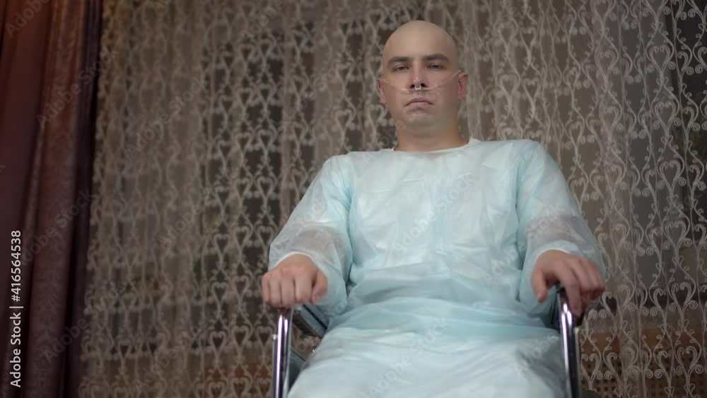 A bald young man with cancer looks at the camera and cries. The patient ...