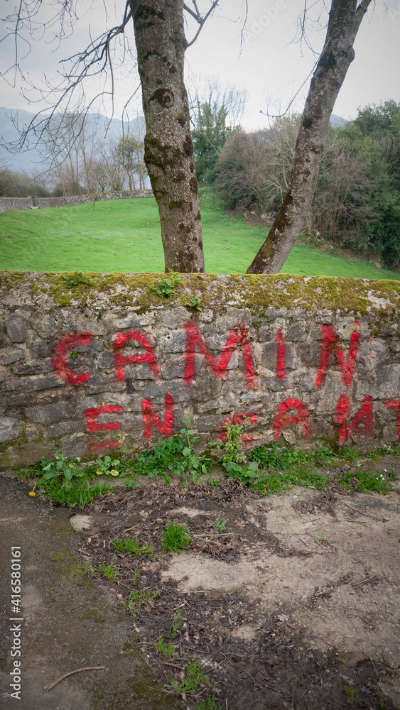 Letras pintadas con spray rojo en muro de piedra en valle verde en ...