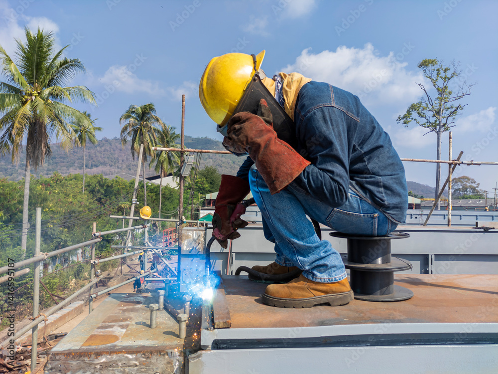 The welder is welding a steel structure work with process Flux Cored ...