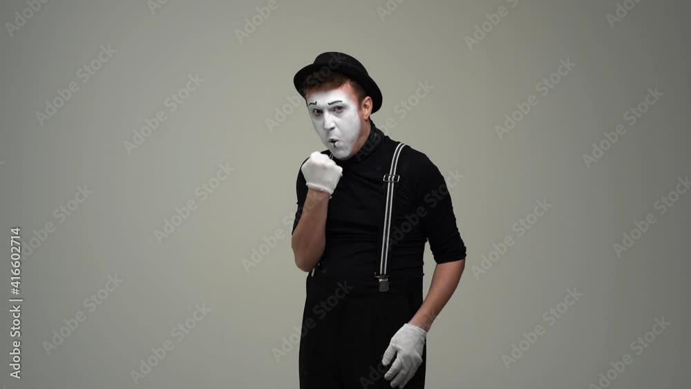 Portrait of angry aggressive male mime spiting on fists, standing in ...