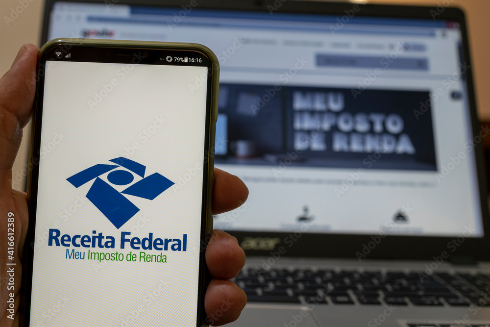 hand holding cell phone with Income Tax application and in the ...