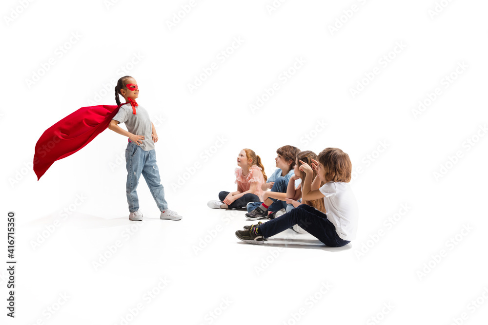 Power. Child pretending to be a superhero with her friends sitting ...