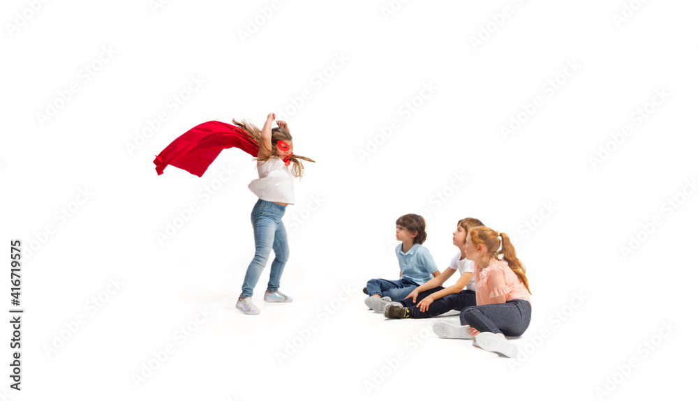 Cool. Child pretending to be a superhero with her friends sitting ...