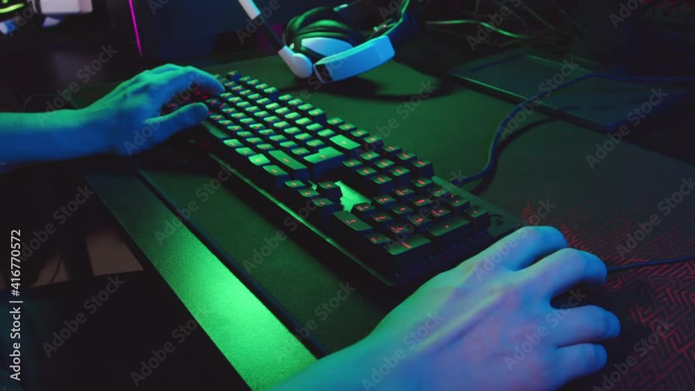 The hands of the gamer are tapping on the keyboard and gaming mouse ...