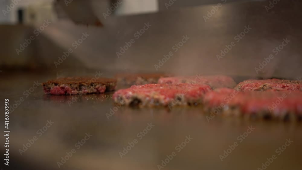 Flipping meat patty on a hot plate in restaurant kitchen. Close up view ...