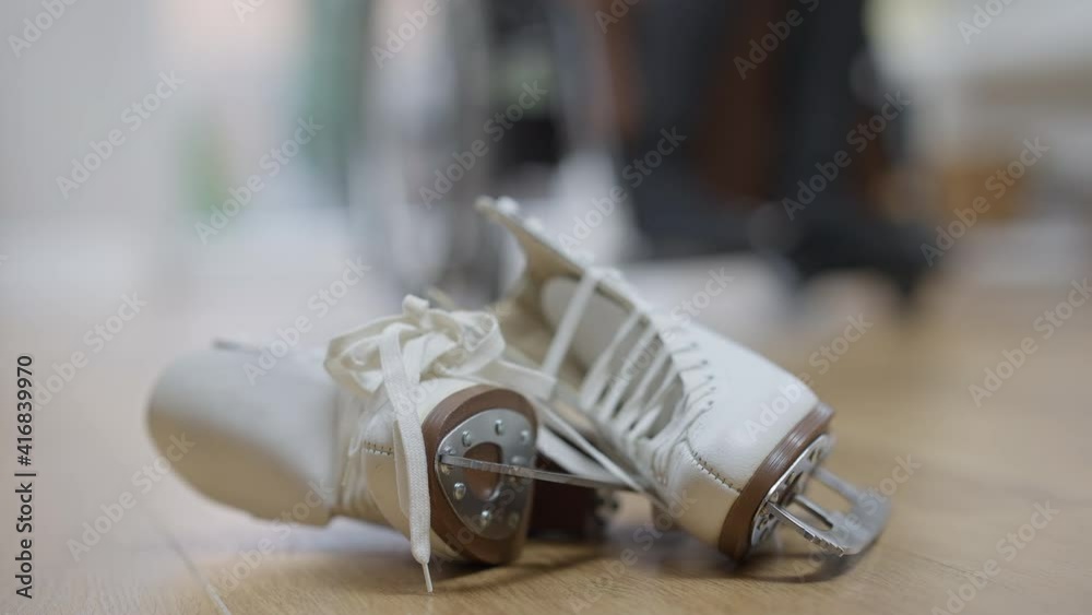 Close-up of ice skates lying on floor indoors with blurred person ...