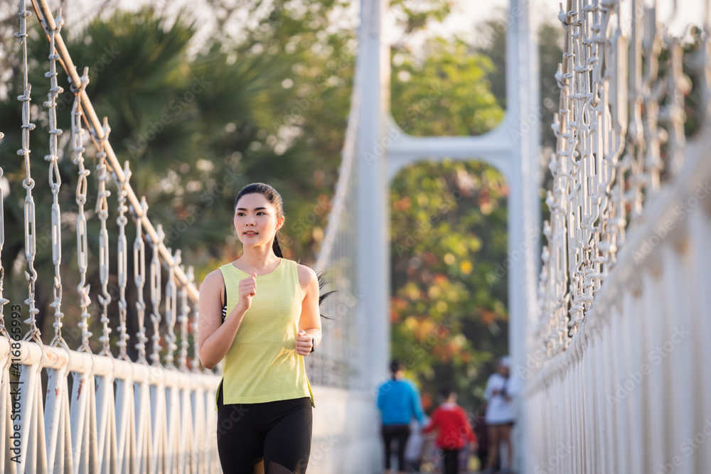 A young Asian woman runner athlete in sports outfit jogging and workout ...