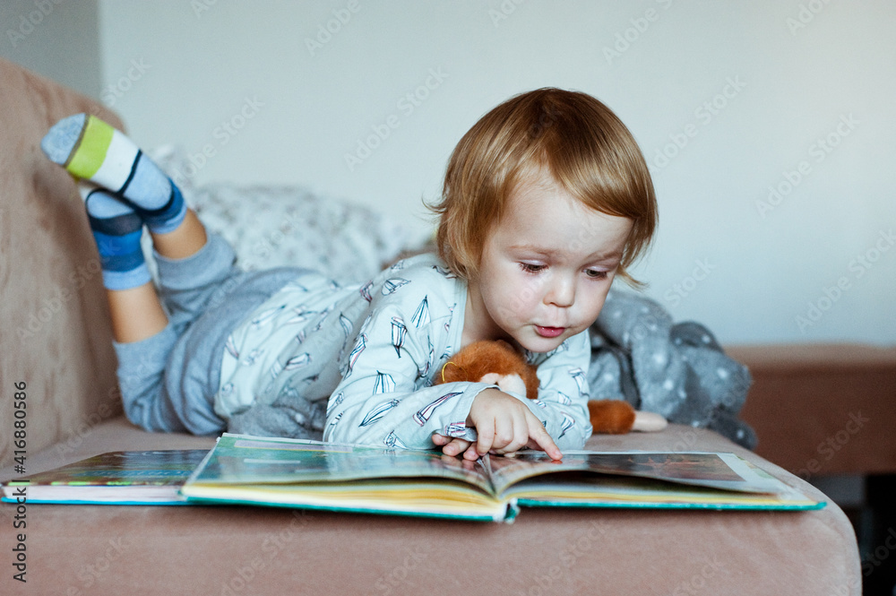 Cute little boy with enthusiasm reads the book. The child likes to read ...