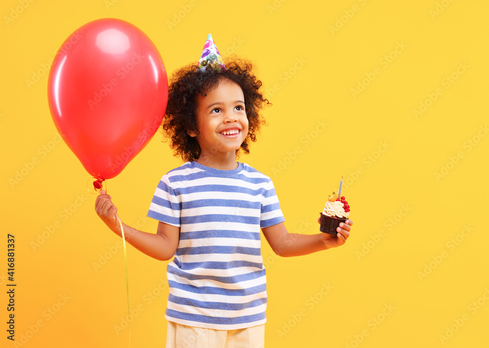 Happy black child with balloon and birthday cupcake smiling in yellow ...