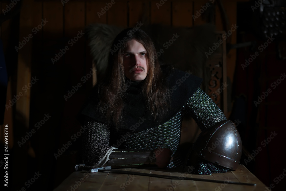 A mighty hero with long hair in chain mail armor in an ancient hall ...