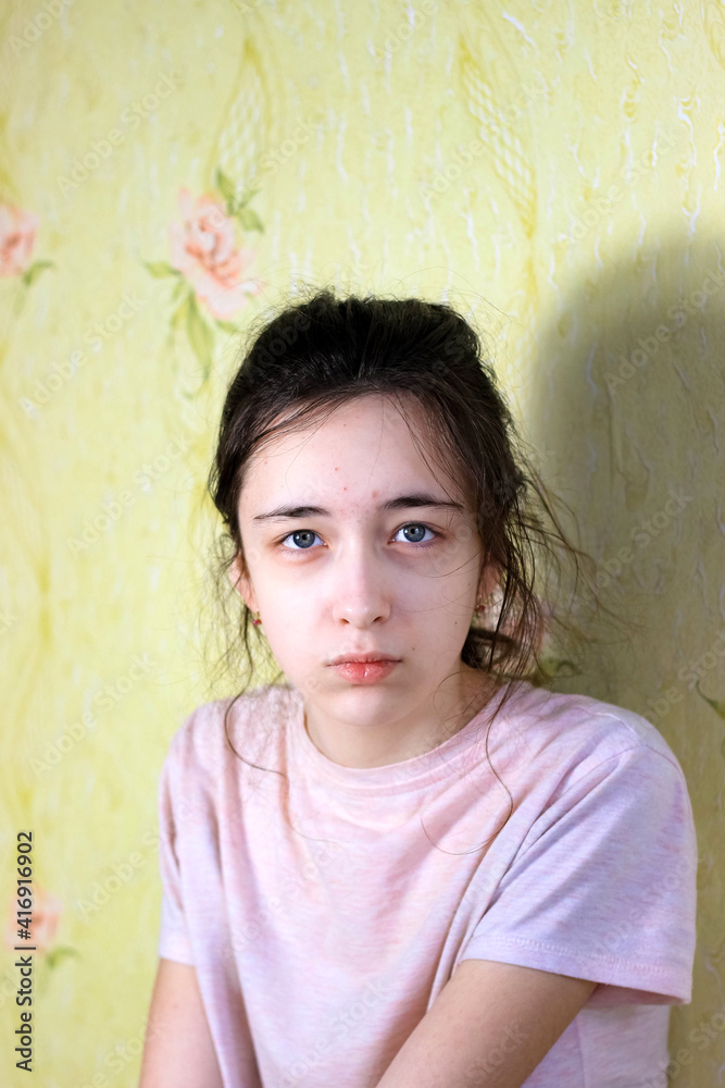 Portrait of a 12-year-old teenage girl with a serious face at home ...