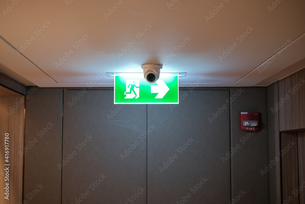 Emergency exit sign at the corridor in building. Green fire exit sign ...