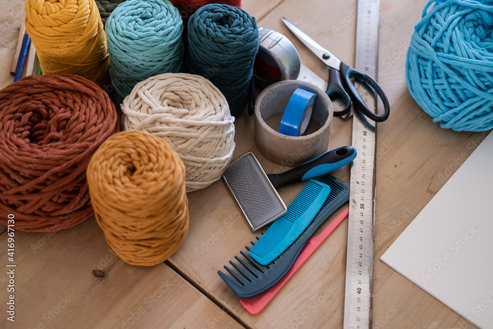 Tools and skeins of colorful threads for creating macrame with your own ...