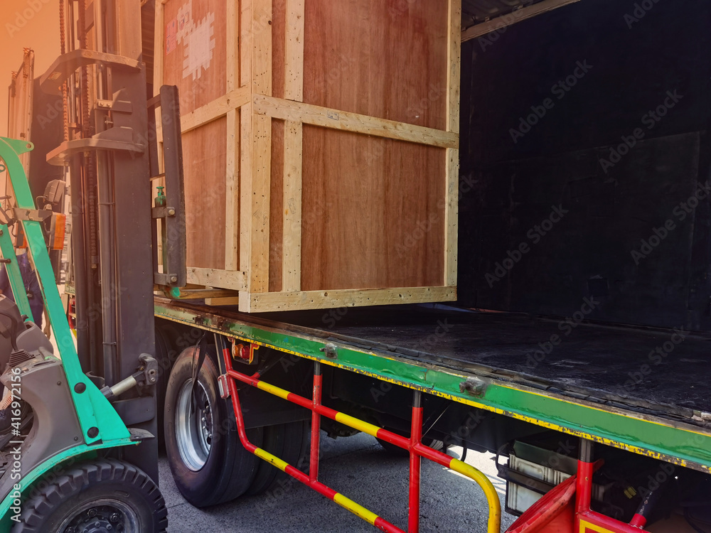 Worker driving forklift loading shipment carton boxes goods on wooden ...