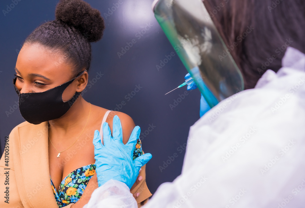 Young black girl receiving the injection of the coronavirus vaccine by ...