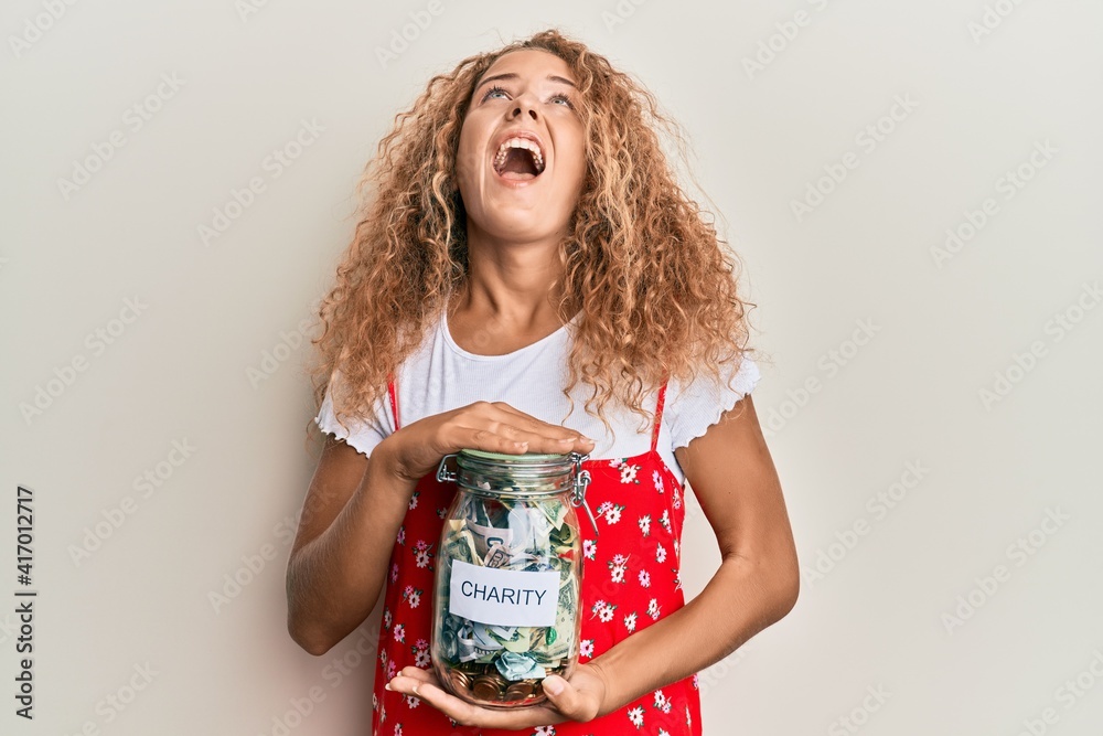 Beautiful caucasian teenager girl holding charity jar with money angry ...