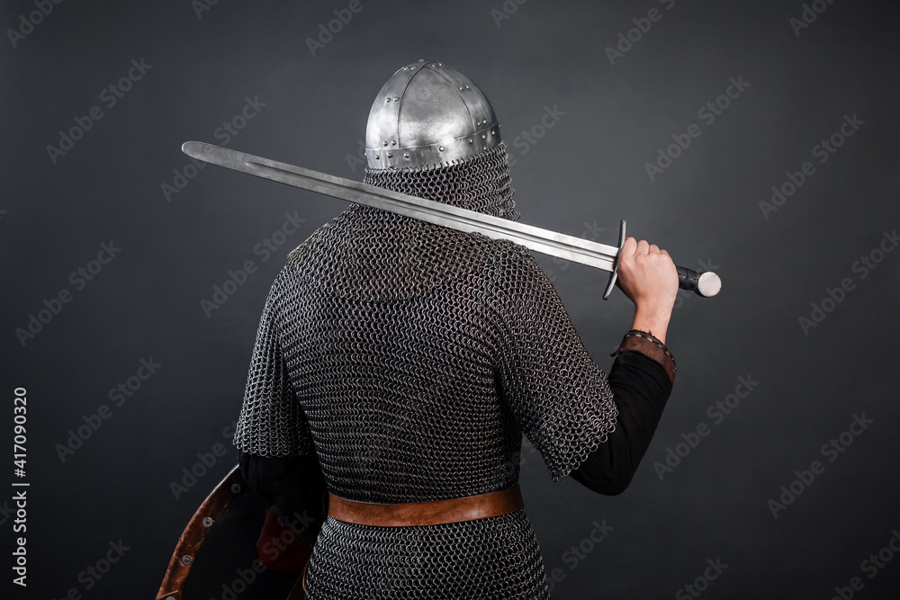 Back view of a knight in chain mail and a helmet with a sword on his ...