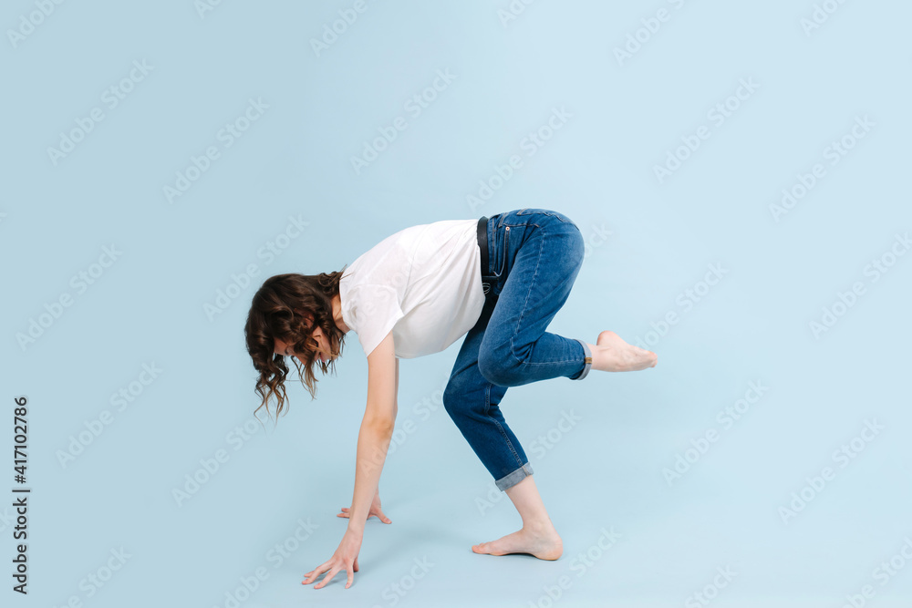 Contemporary dancer poses in front of blue studio background. She's ...