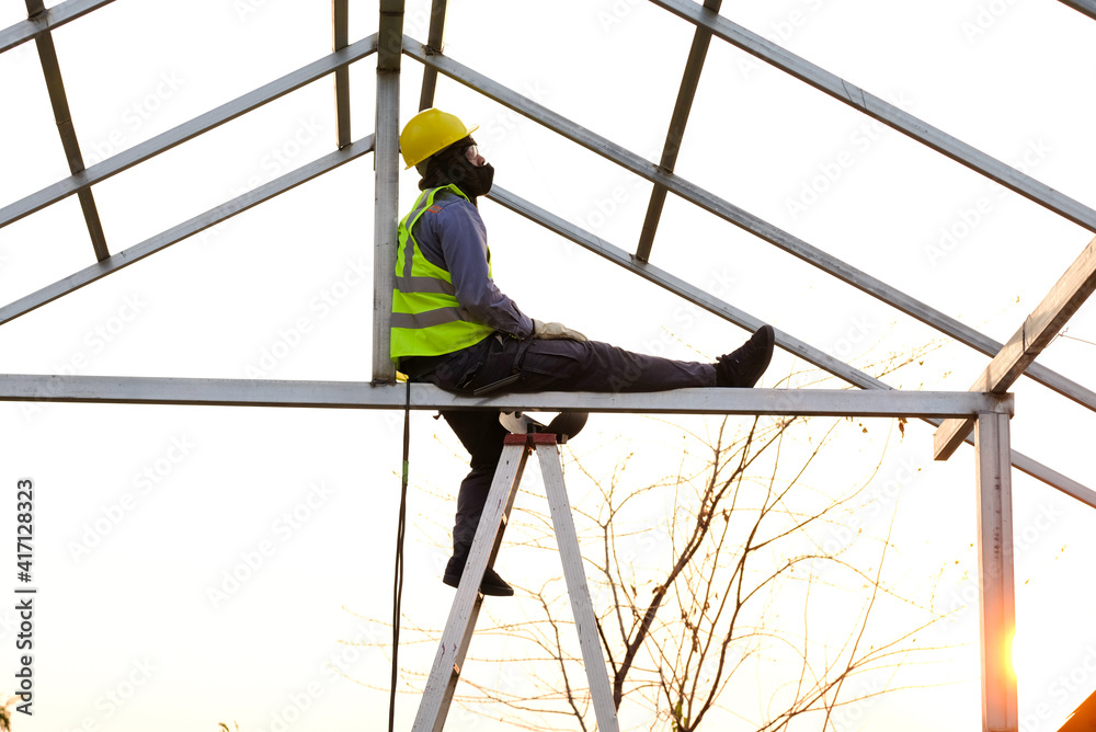 Roofing workers working on roof trusses on a construction site are ...