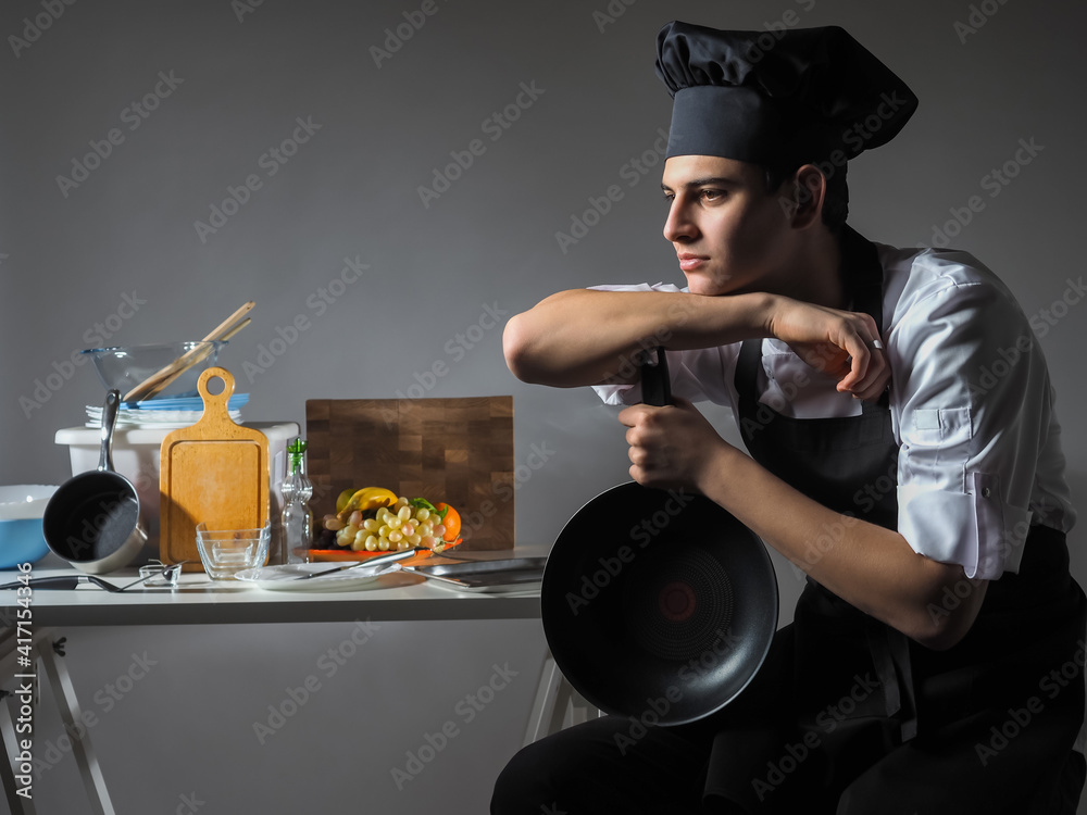 Chef is waiting for order. Man cook is sitting with a frying pan in his ...